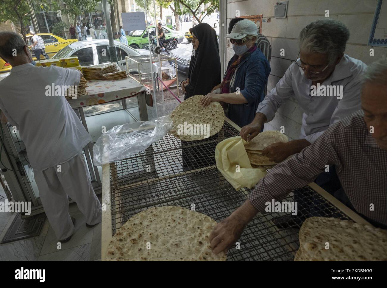 Iranian people collect bread while shopping at a bakery near the ...