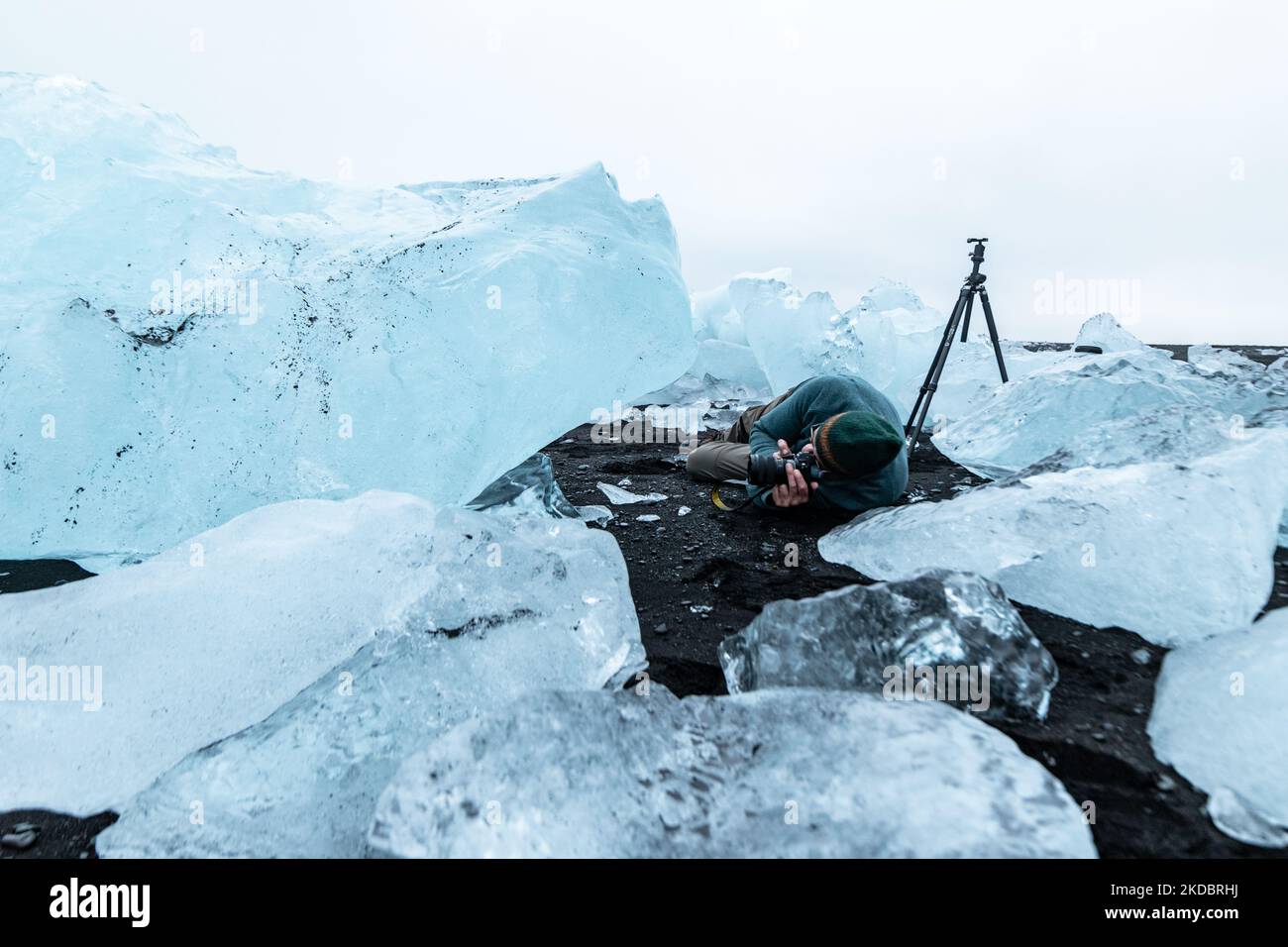 A photographer laying on the beach with big frozen ice blocks Stock ...