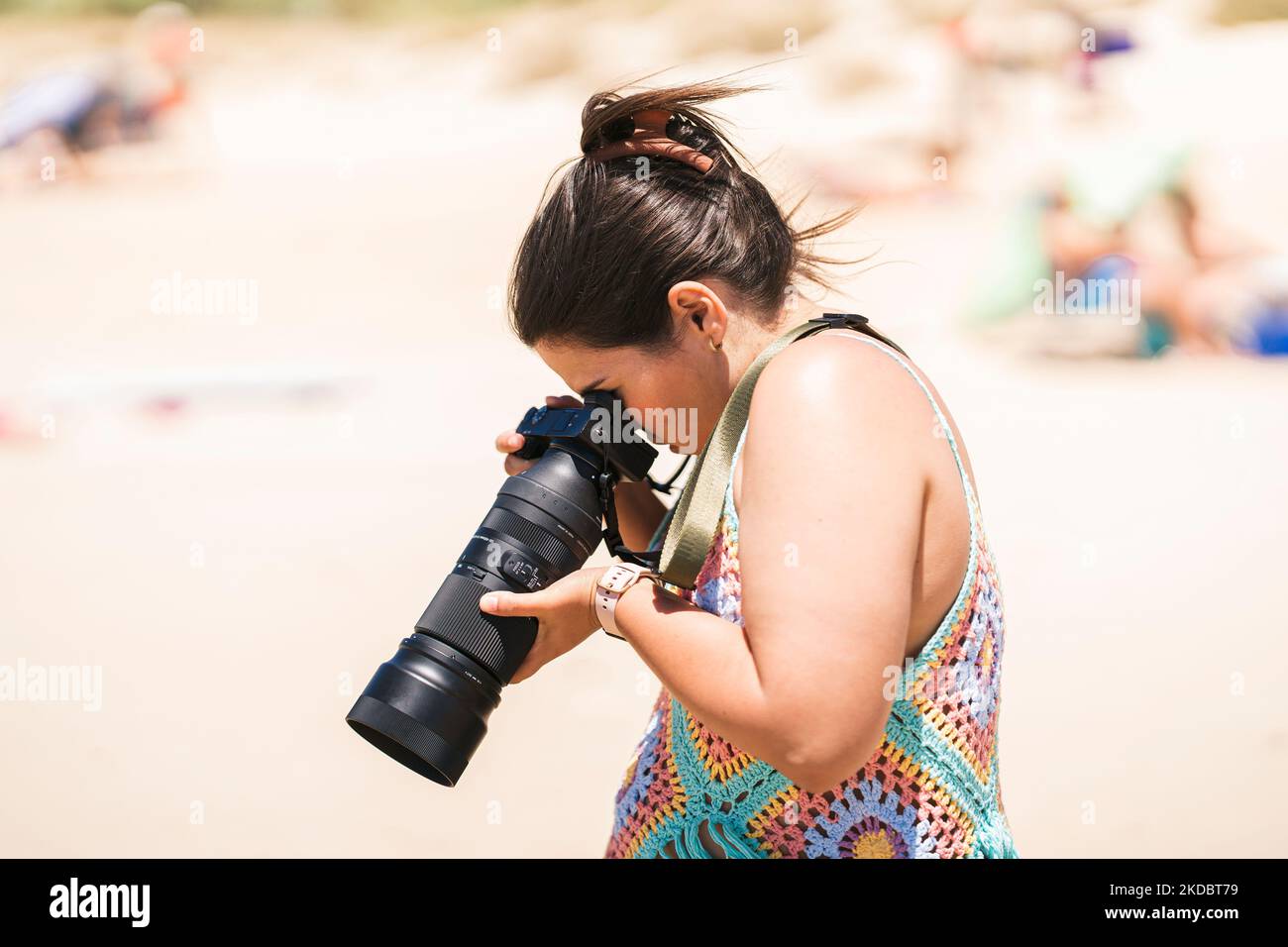 A Caucasian female taking photos at a beach with a professional camera ...
