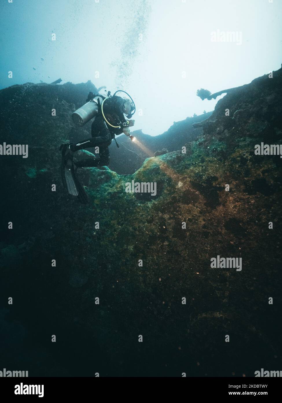 A scuba diver exploring the mysterious ship wrecks, in a vertical shot ...