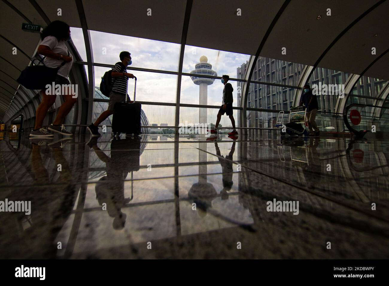 Travellers walk across a link bridge linking terminals at Changi ...