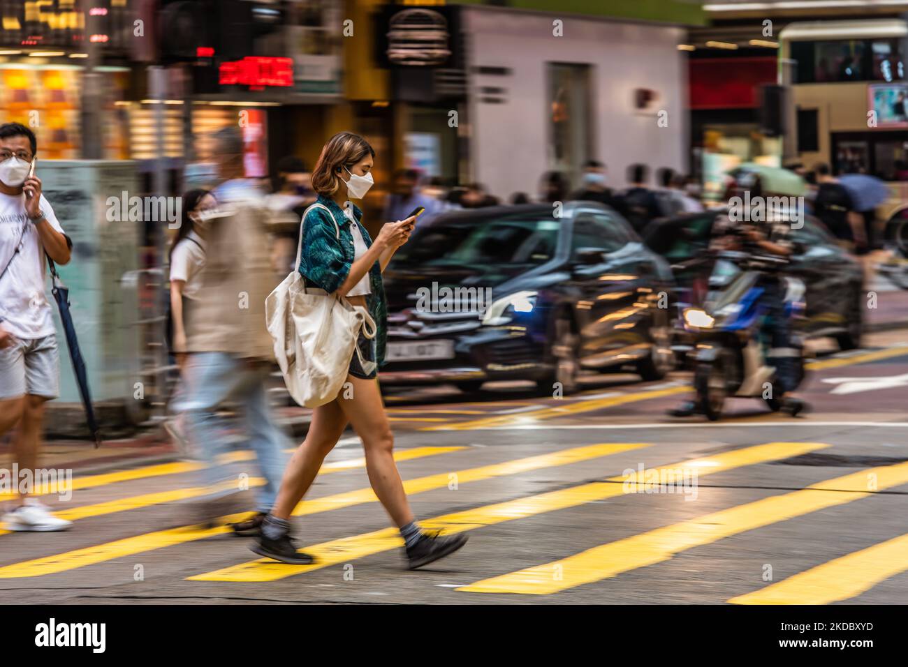 Hong Kong, China, 11 Jun 2022, A masked young lady crosses a street in ...