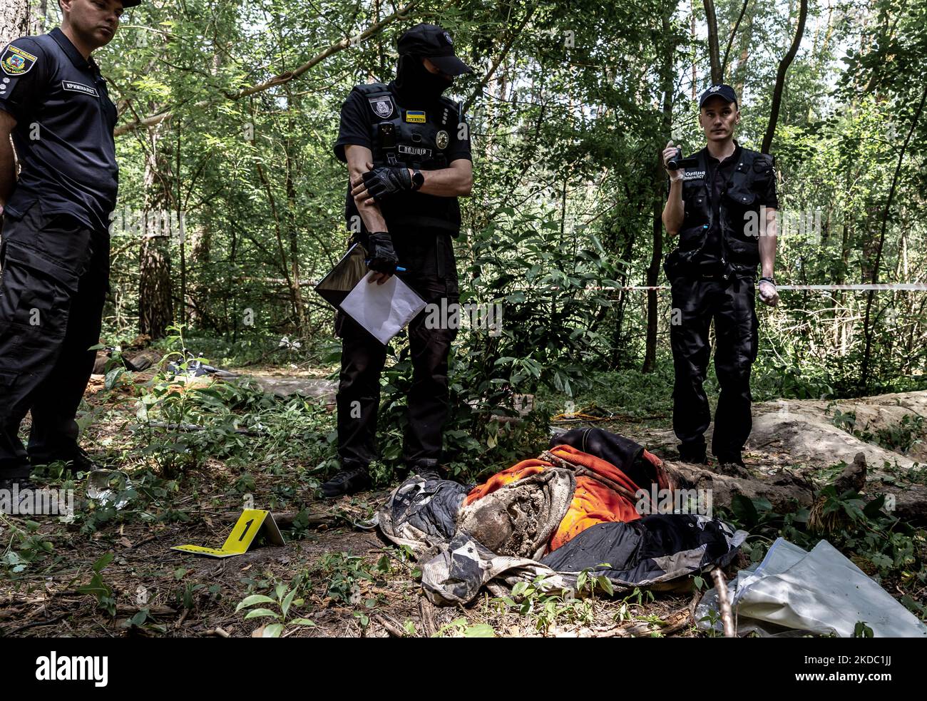 Policemen work in a forest near Bucha, Ukraine during excavation of ...