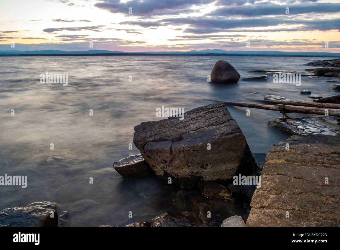 A beautiful scene of lakeside with rocks and dramaric sunset sky on the ...