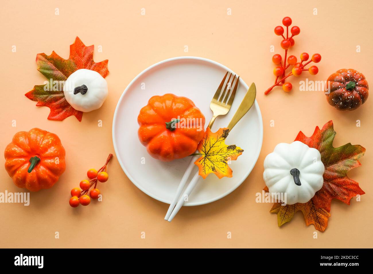 Autumn table setting. White plate, golden cutlery and fall decorations ...