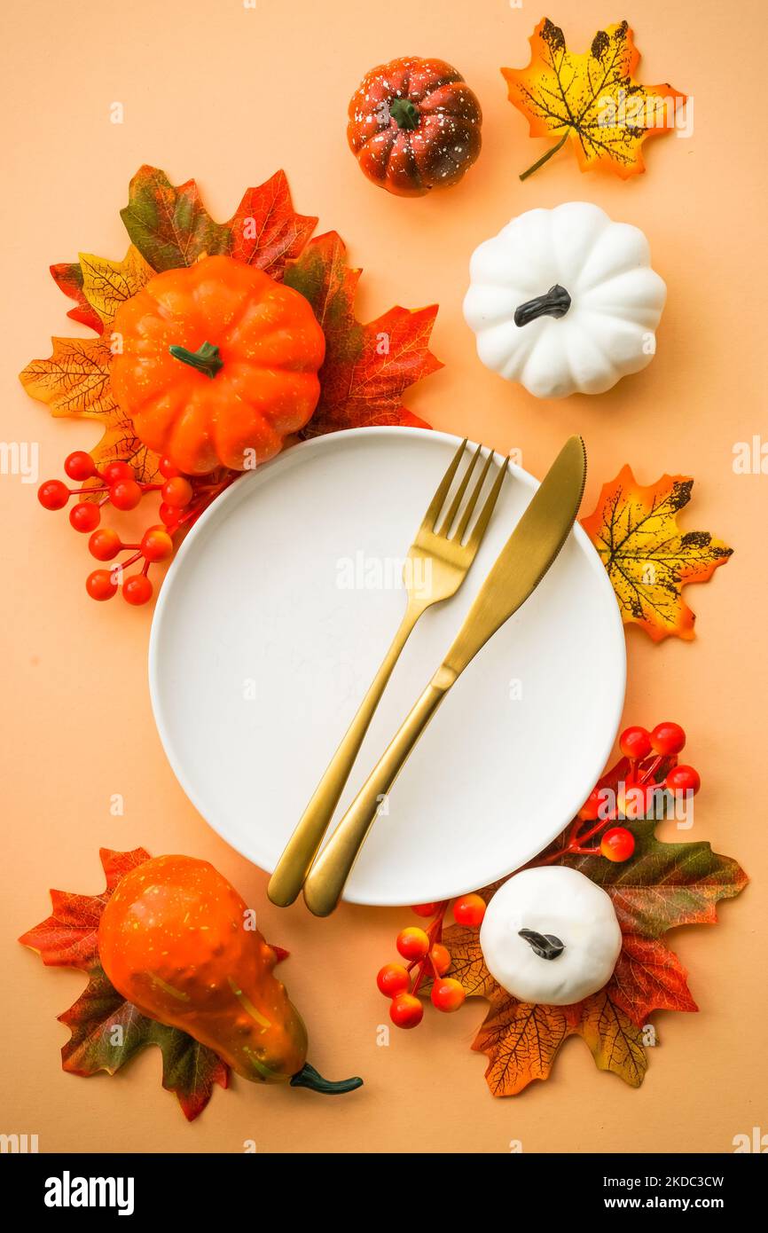 Autumn table setting. White plate, golden cutlery and fall decorations ...