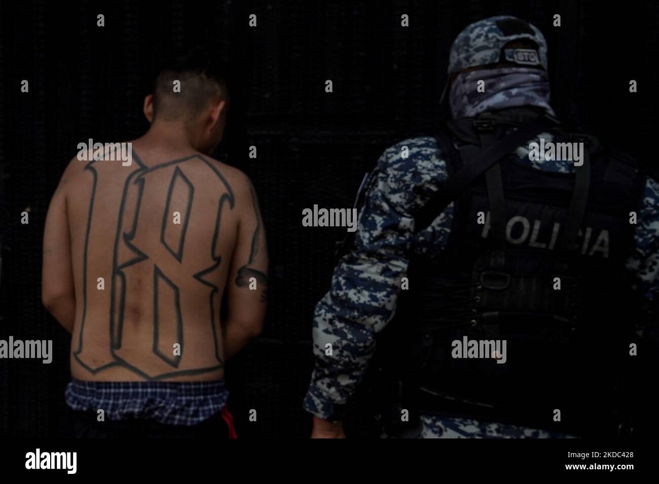 A police officer escorts a Barrio-18 gang member into a detention ...