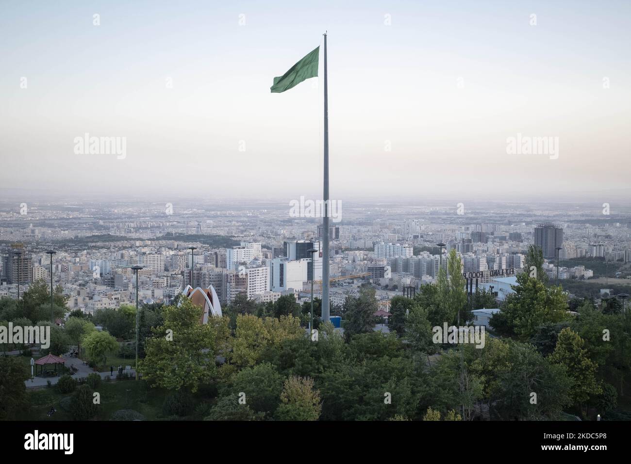 A green flag waves while a view of residential and commercial complexes ...