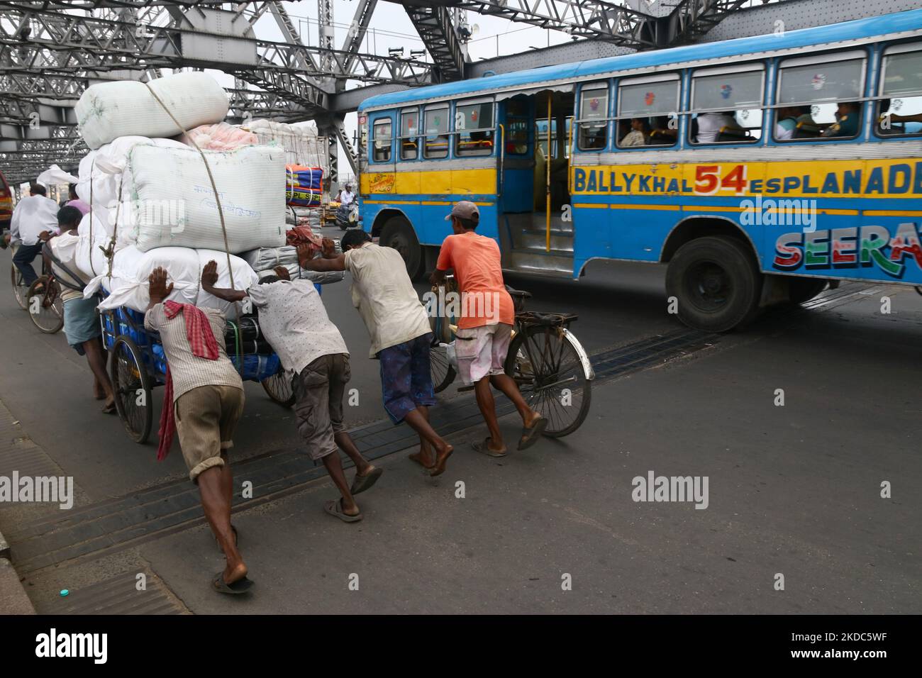 Indian Laborers push a cycle van loaded Goods across the Howrah Bridge ...