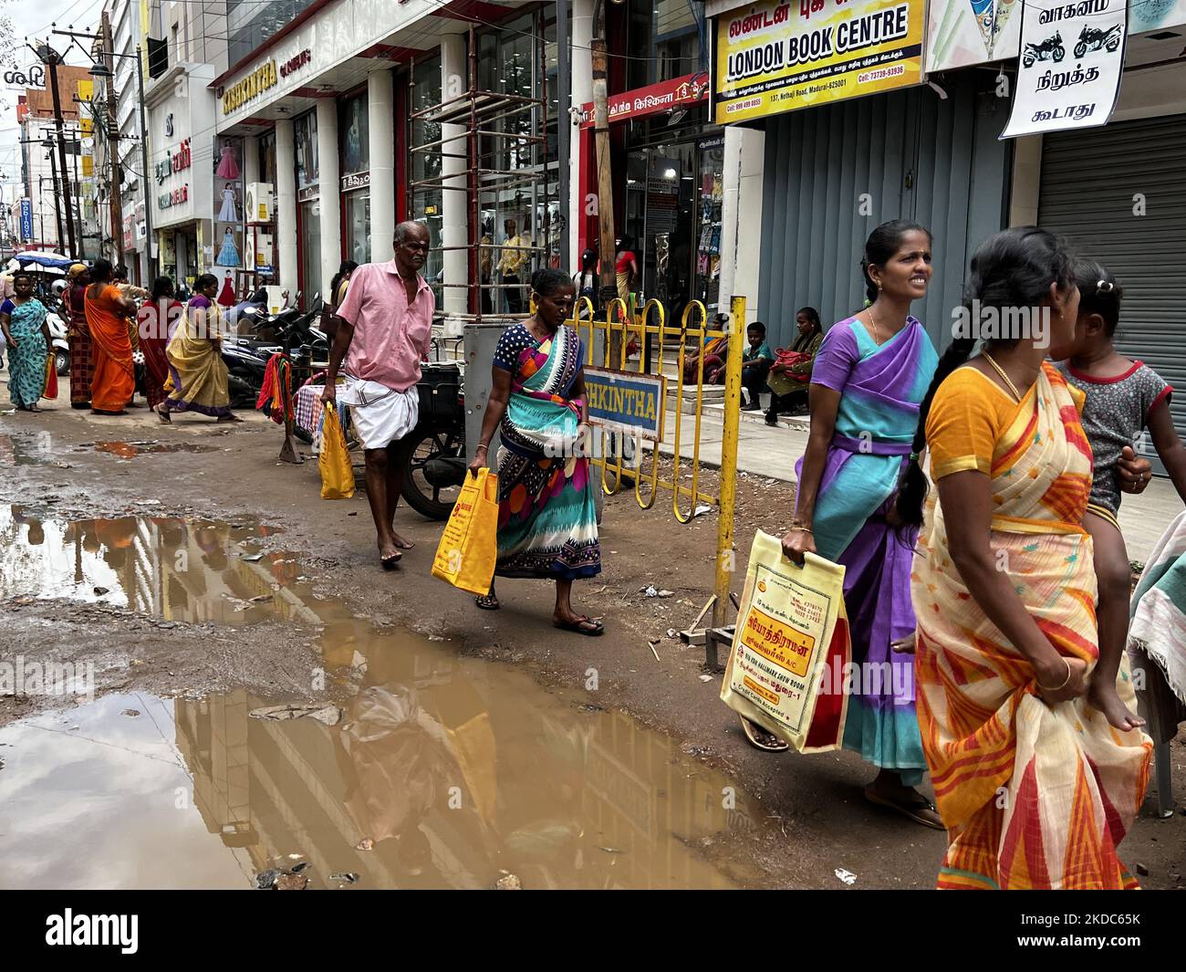 People walk along an unpaved street in Madurai, Tamil Nadu, India on ...