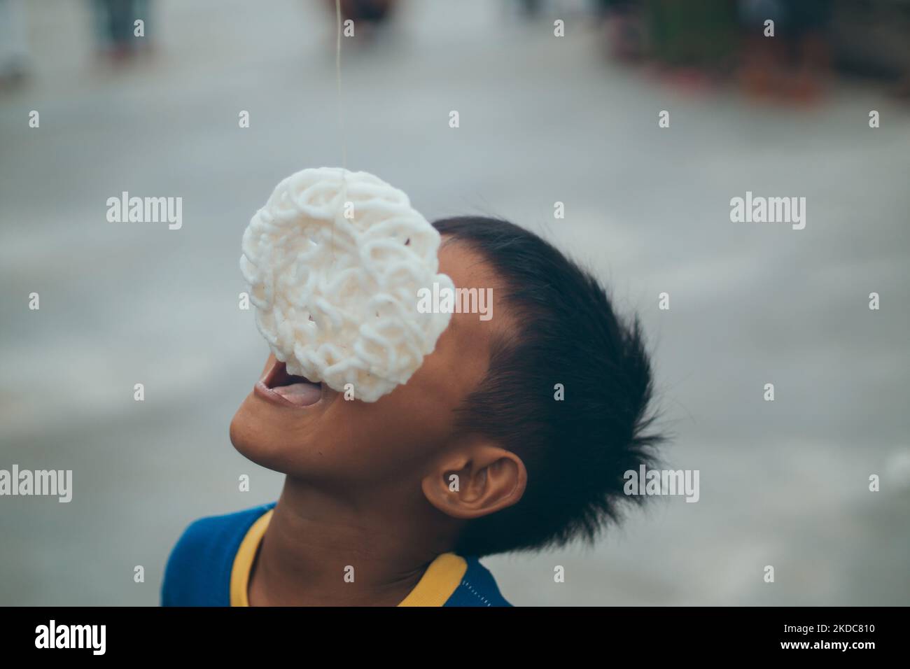 A child playing a game, trying to eat the hanging cracker in order to ...