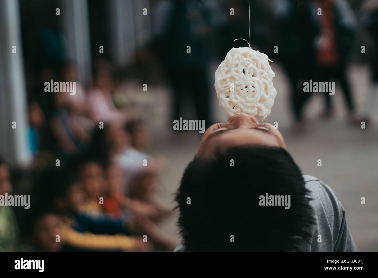 A child playing a game, trying to eat the hanging cracker in order to ...