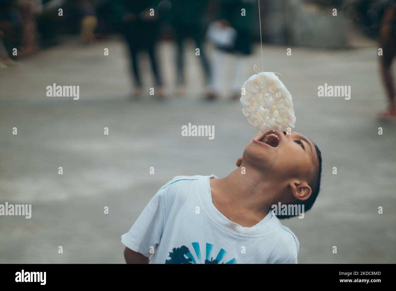A child playing a game, trying to eat the hanging cracker in order to ...