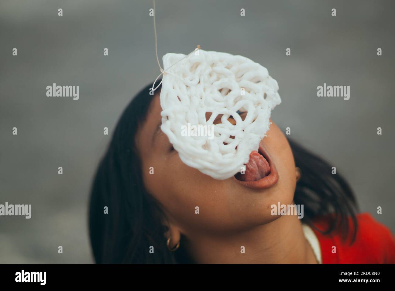 A child playing a game, trying to eat the hanging cracker in order to ...