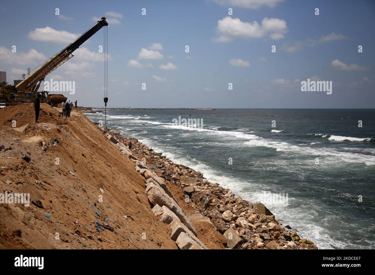 Palestinian construction workers build a seawall, from the rubble of ...