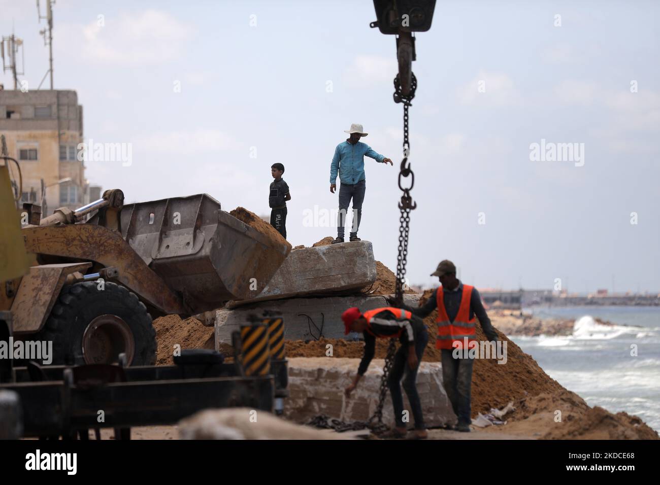 Palestinian construction workers build a seawall, from the rubble of ...