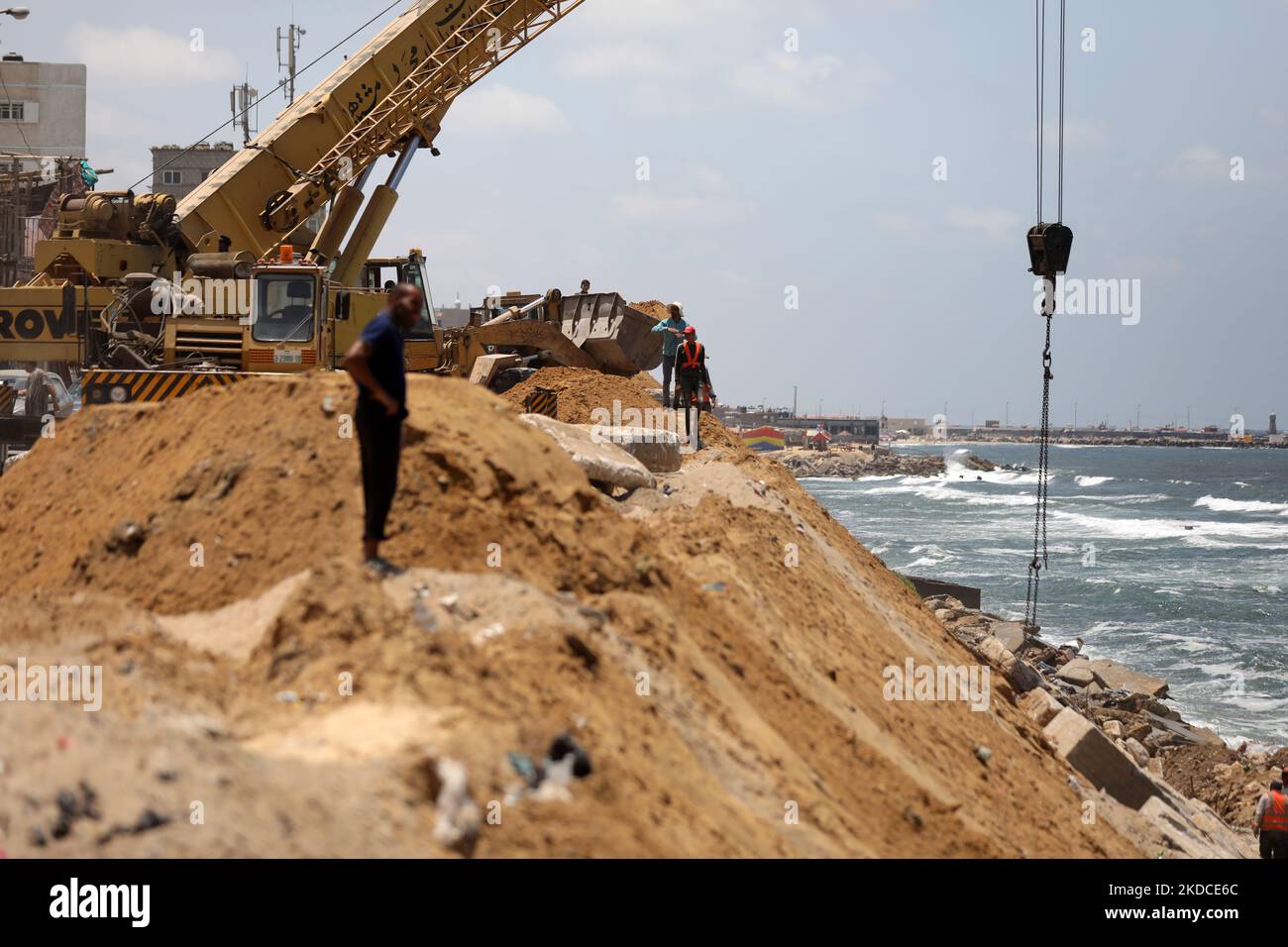 Palestinian construction workers build a seawall, from the rubble of ...