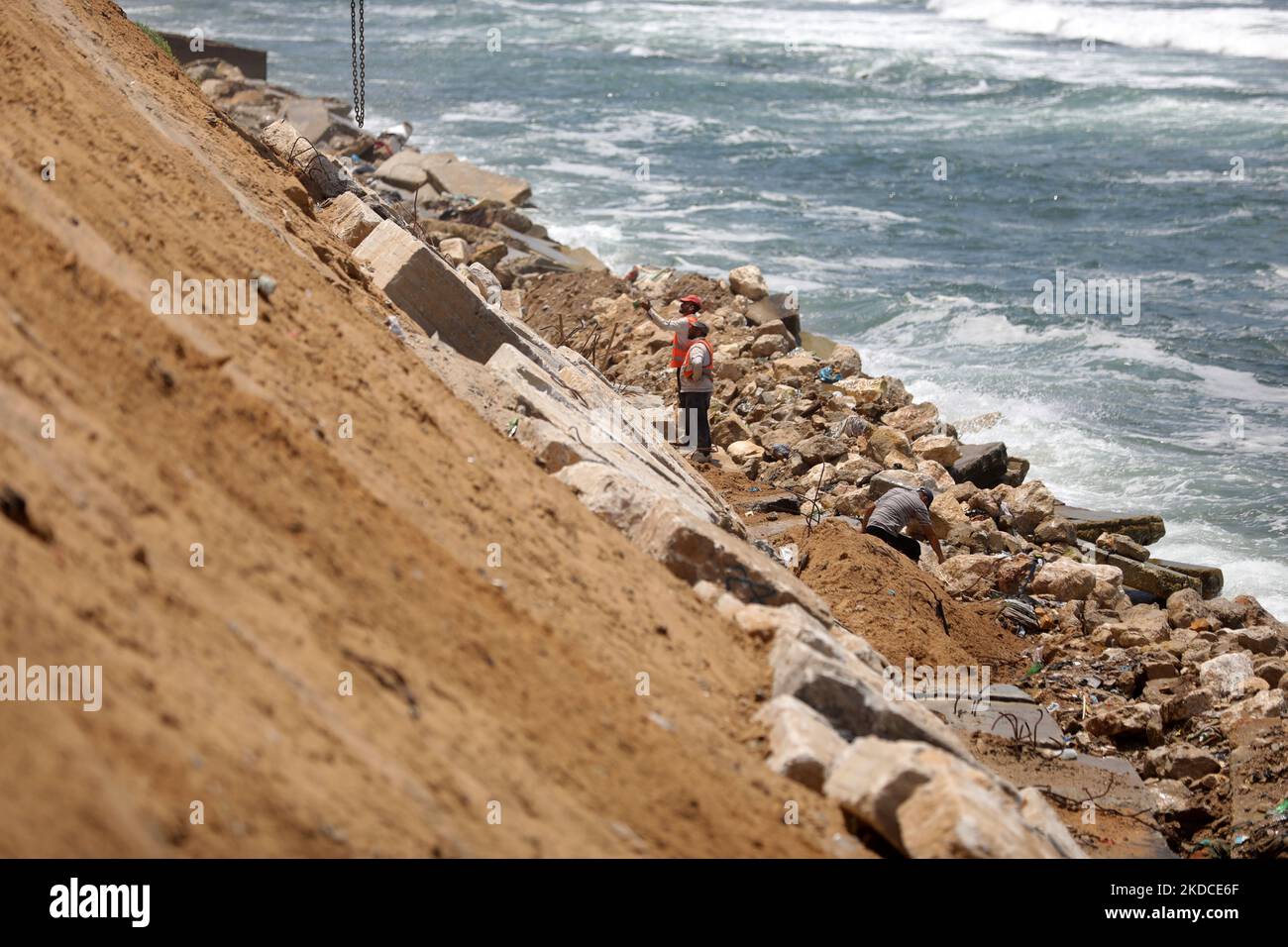 Palestinian construction workers build a seawall, from the rubble of ...