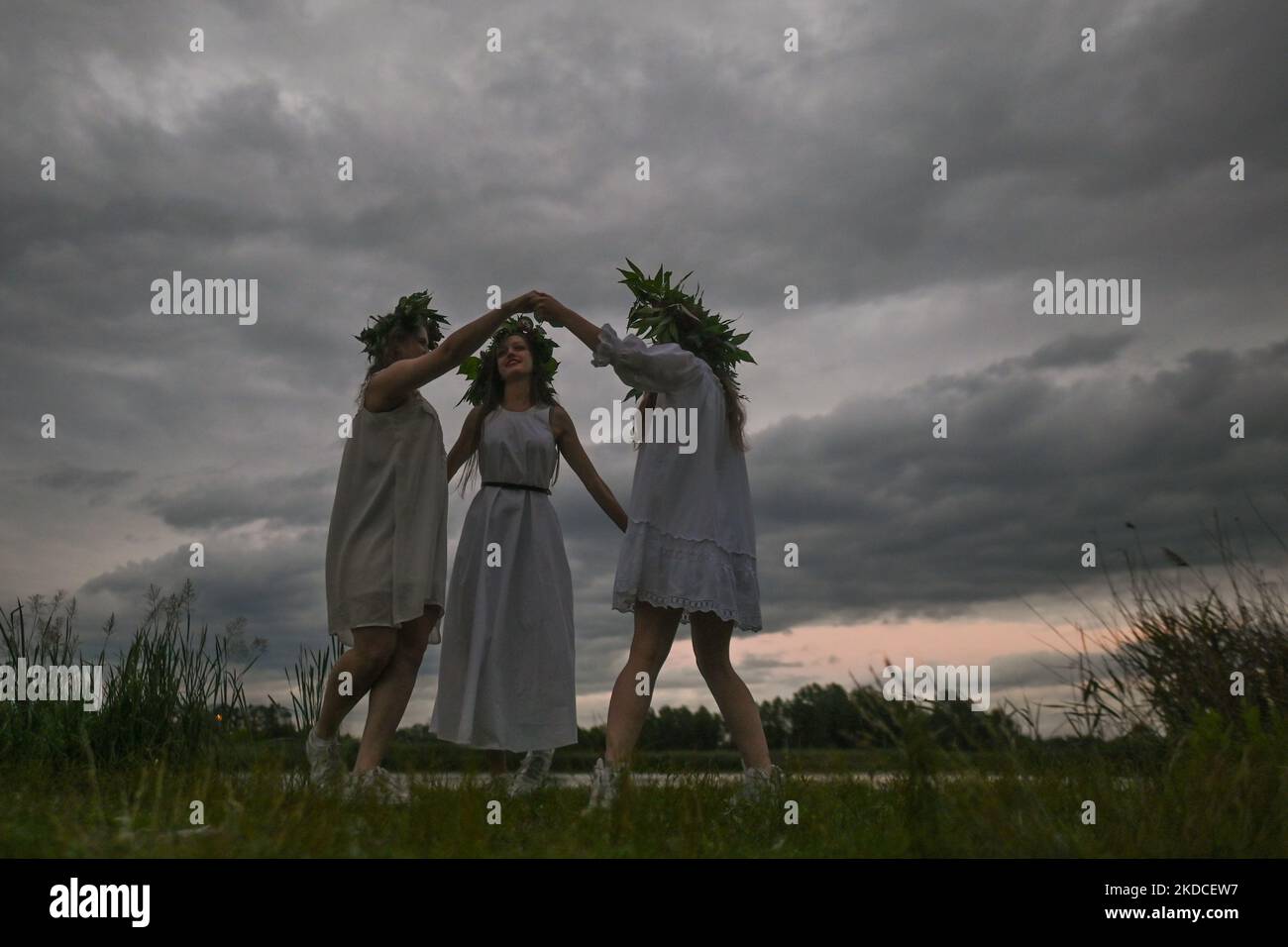 Three young women in a flower wreaths dancing by the Wislok River ...