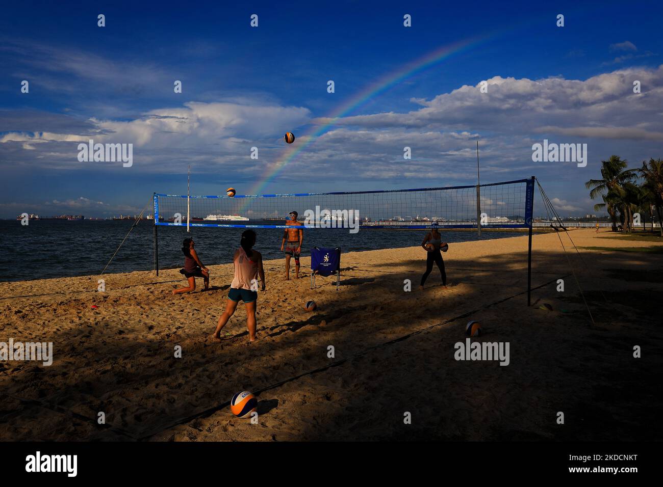 A rainbow is seen as people play beach volleyball at East Coast Park on ...