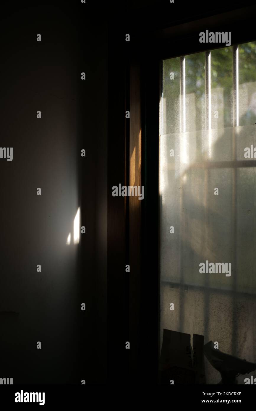 A vertical shot of sunlight on the wall coming from a glass window with ...