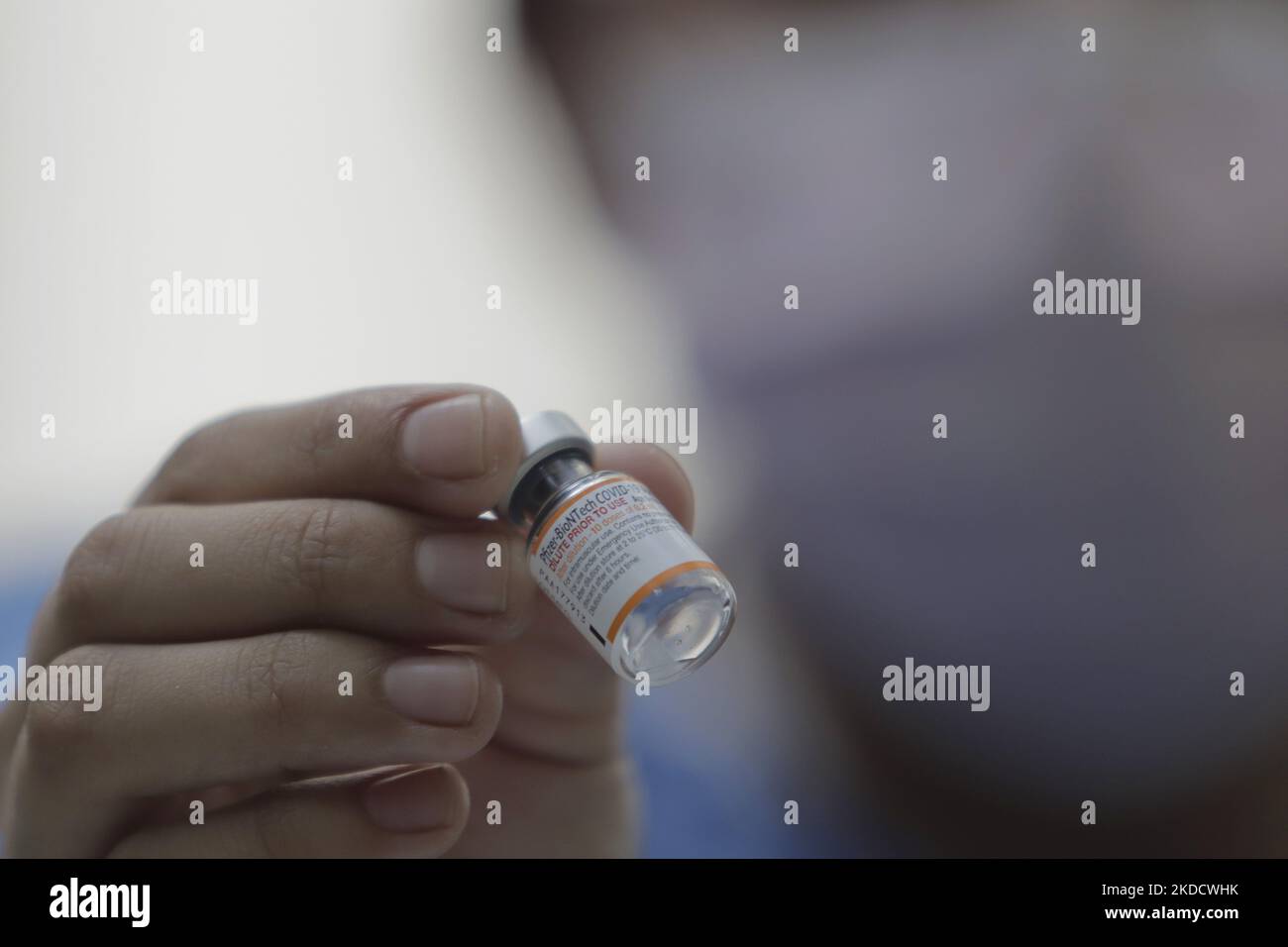 Medical staff hold an empty vial of the Pfizer-BioNTech biologic inside ...