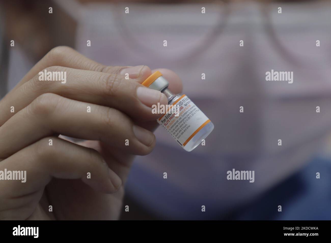 Medical staff hold an empty vial of the Pfizer-BioNTech biologic inside ...