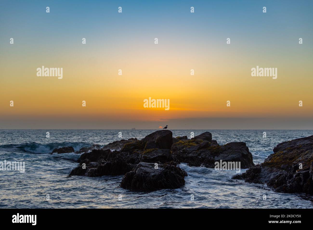 A sunset over the coast of Chile, cliffs on the water with a long ...