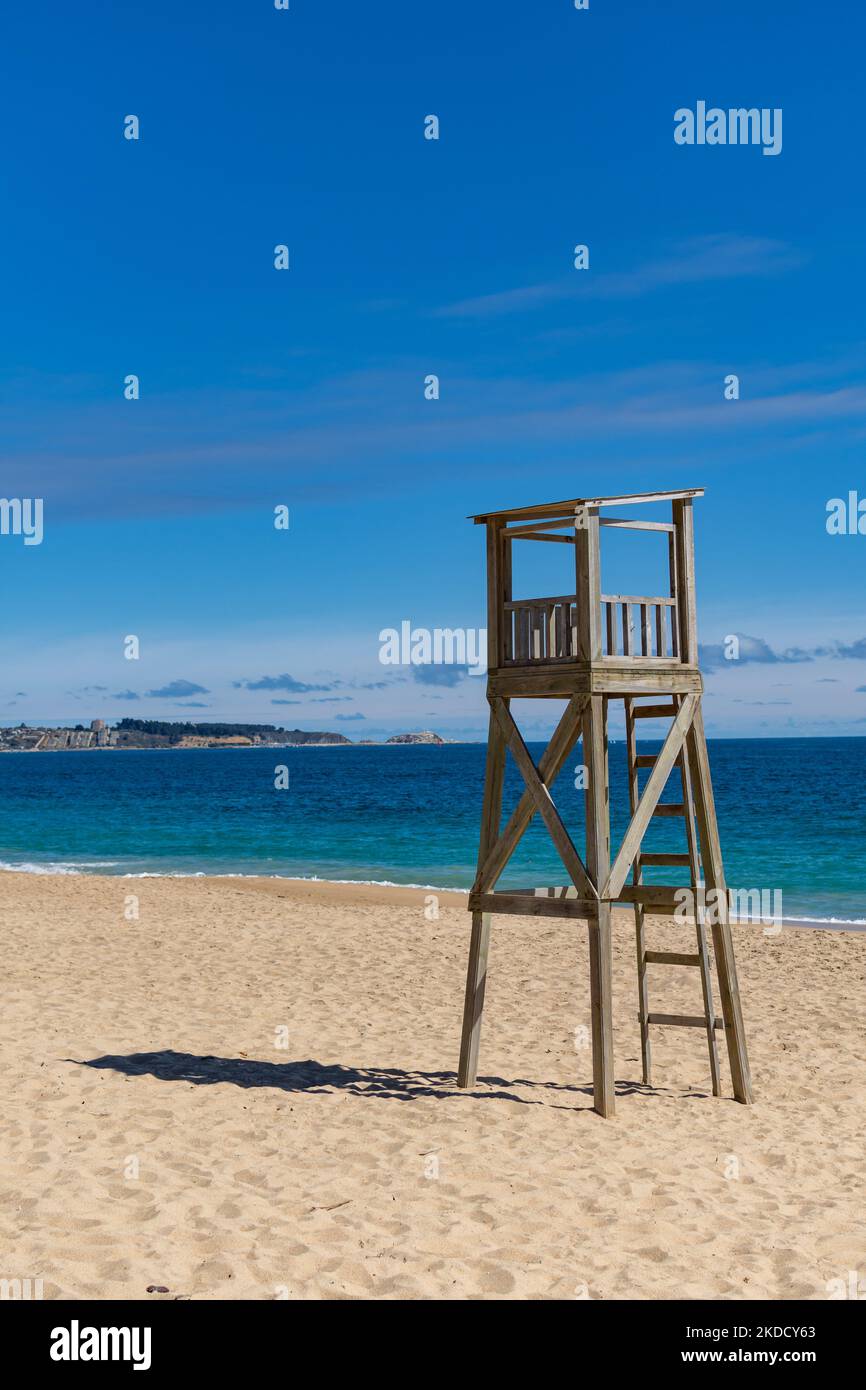 A vertical closeup of a wooden life guard tower on the sandy beach ...