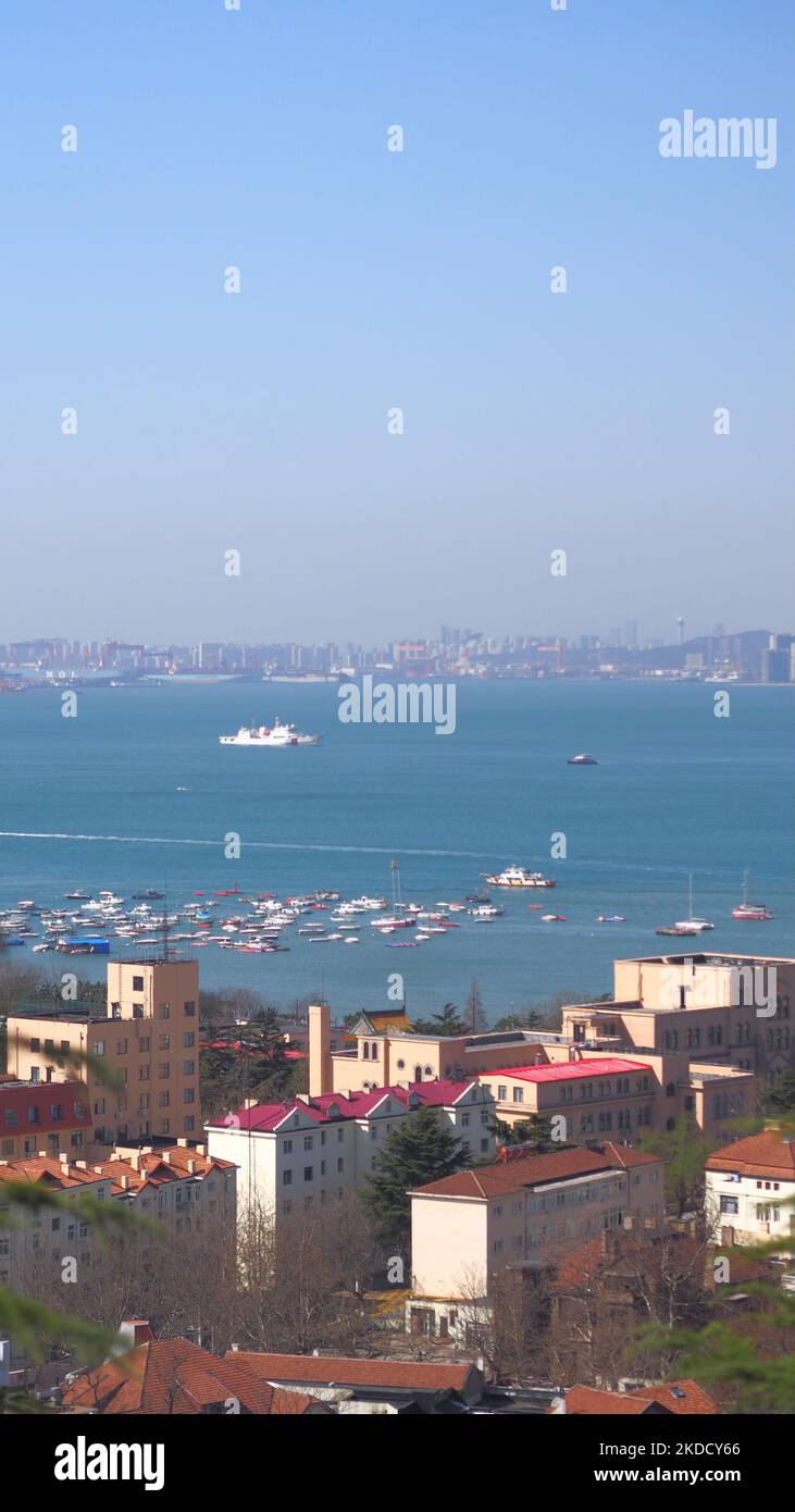 A high-angle vertical of cityscape with the sea and clear sky blurred ...