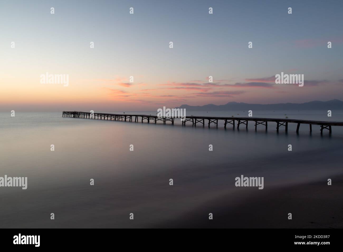 A mesmerizing shot of a wooden dock in a calm sea, with beautiful ...