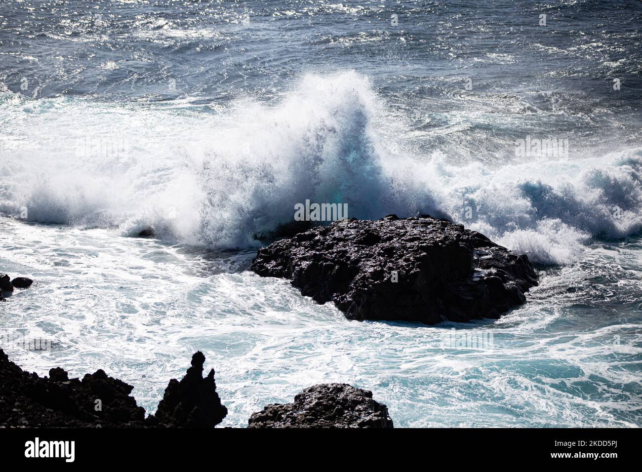 A closeup of a water wave hitting the rock and making a high wave ...