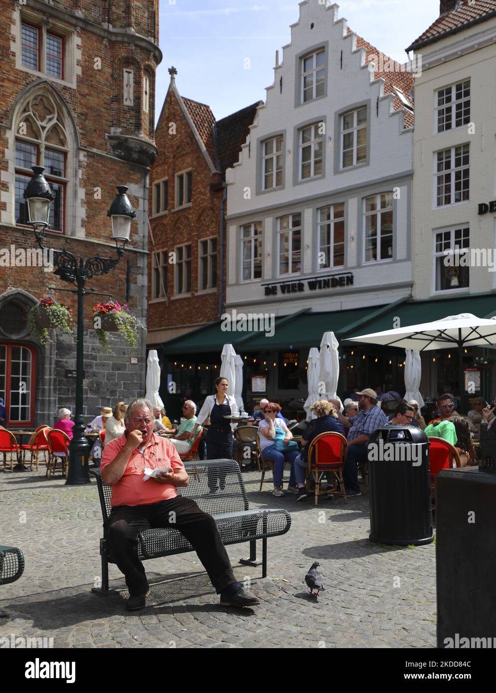 A man is relaxing on a bench eating French fries at the Market Square ...
