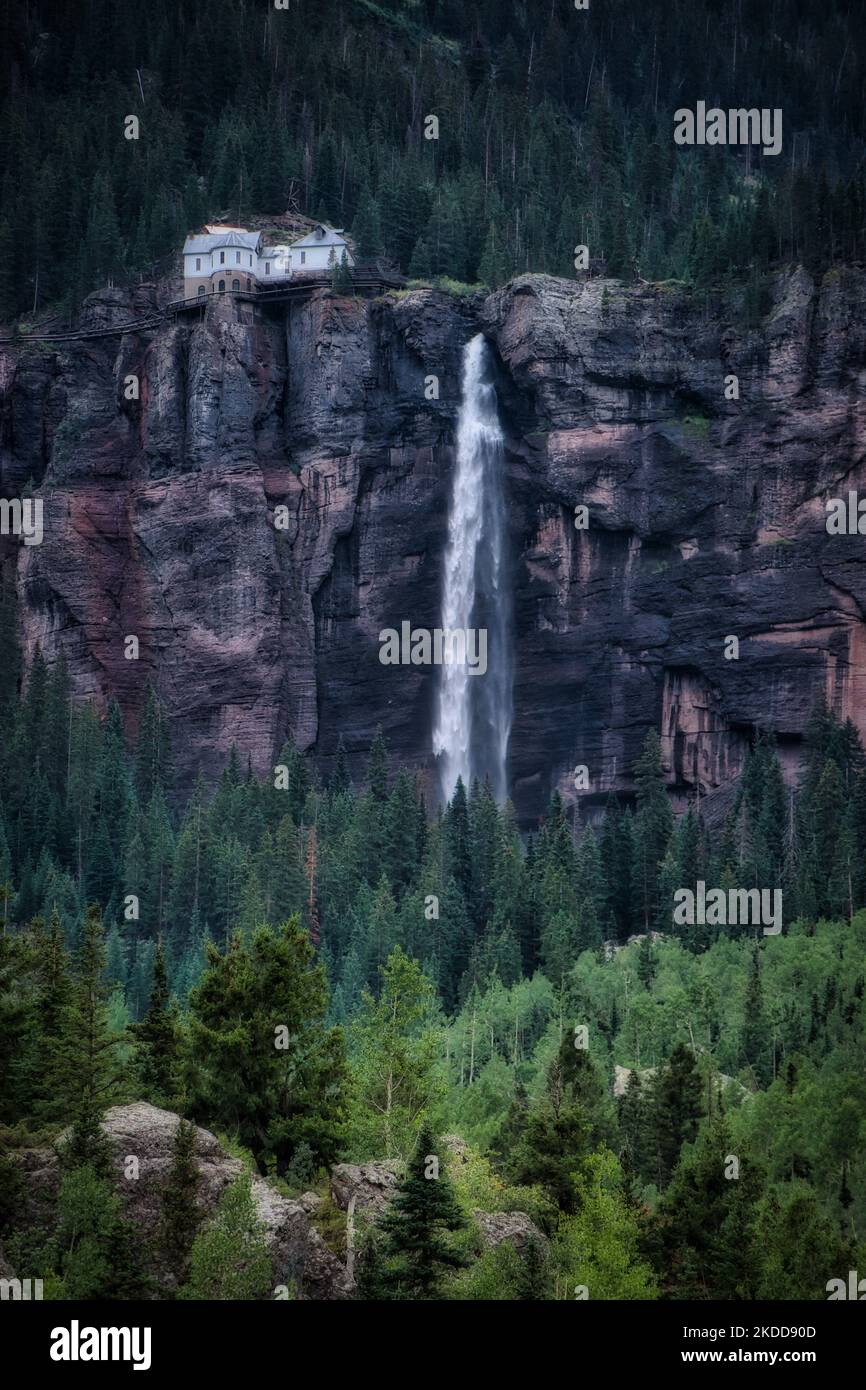 A scenic vertical shot of a beautiful waterfall in an evergreen forest ...