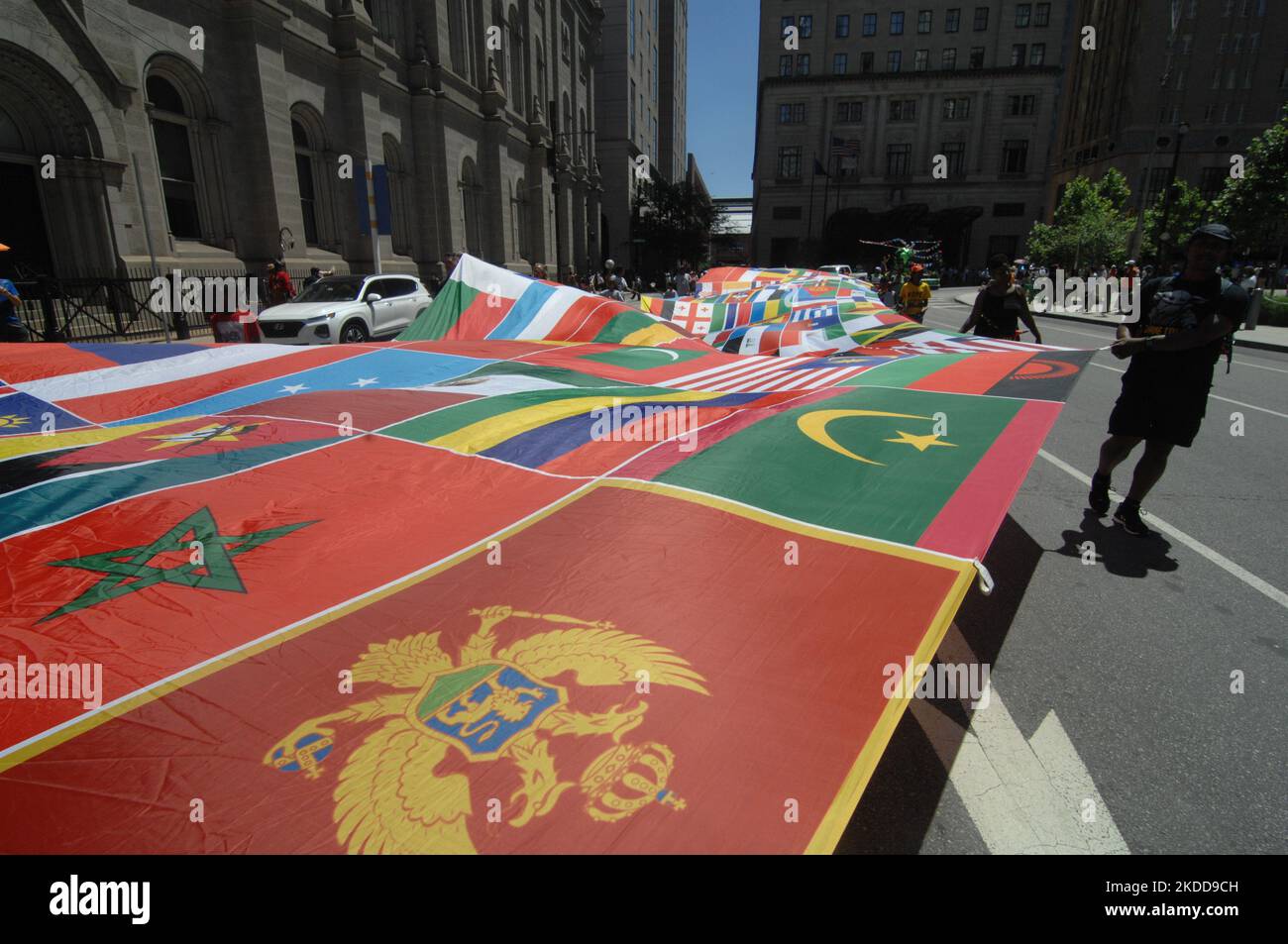 Marchers carry a multinational ribbon of flags stretching nearly a city ...