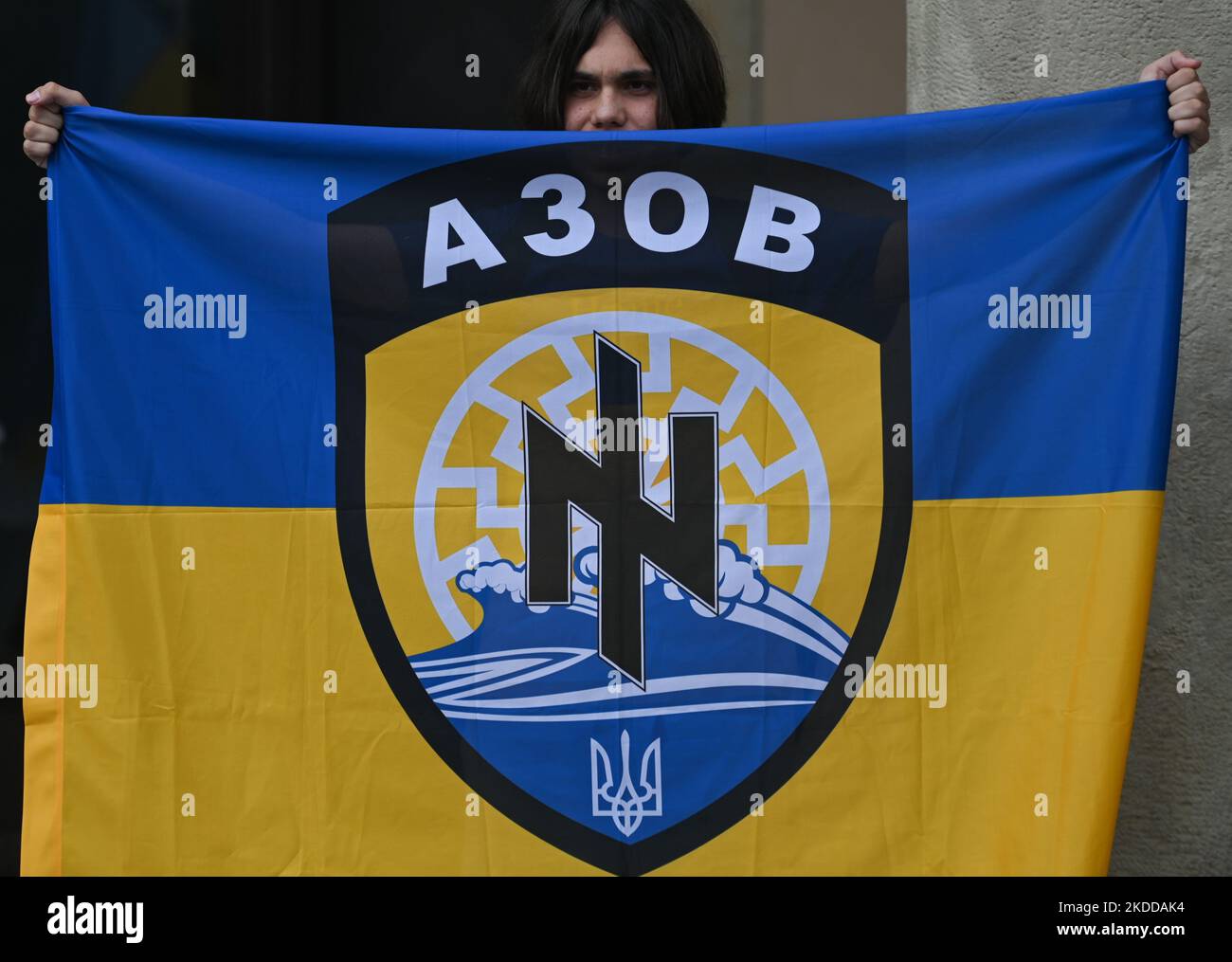 A protester is holding a Ukrainian flag with the logo of the Azov ...