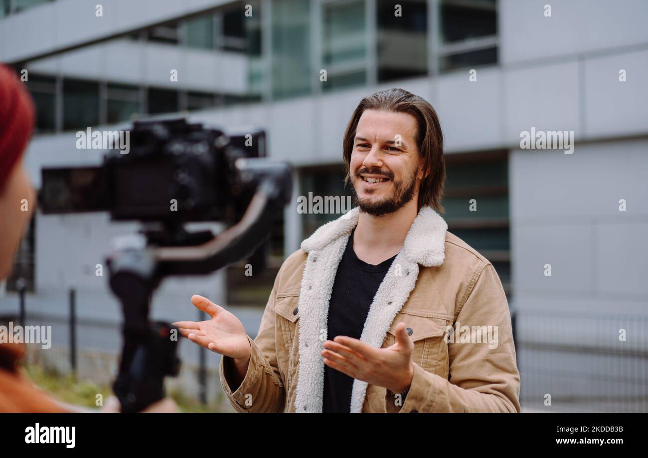 Long haired actor man talking gesturing while cameraman shooting him in ...