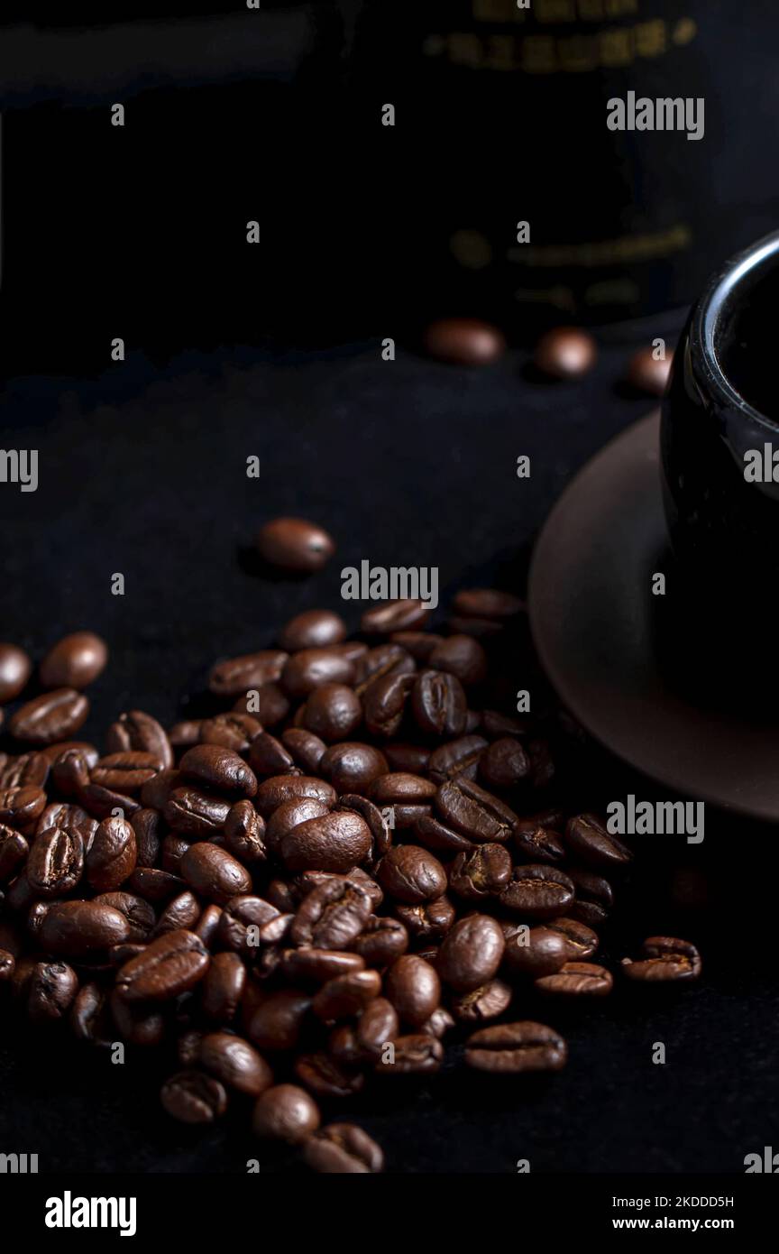 A vertical of coffee beans with a coffee cup isolated on a dark ...
