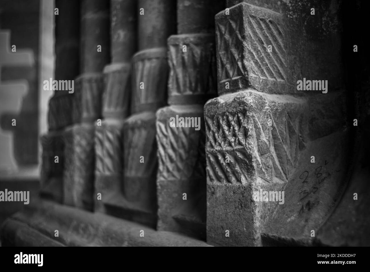 A closeup selective focus grayscale of a stone column base with a ...