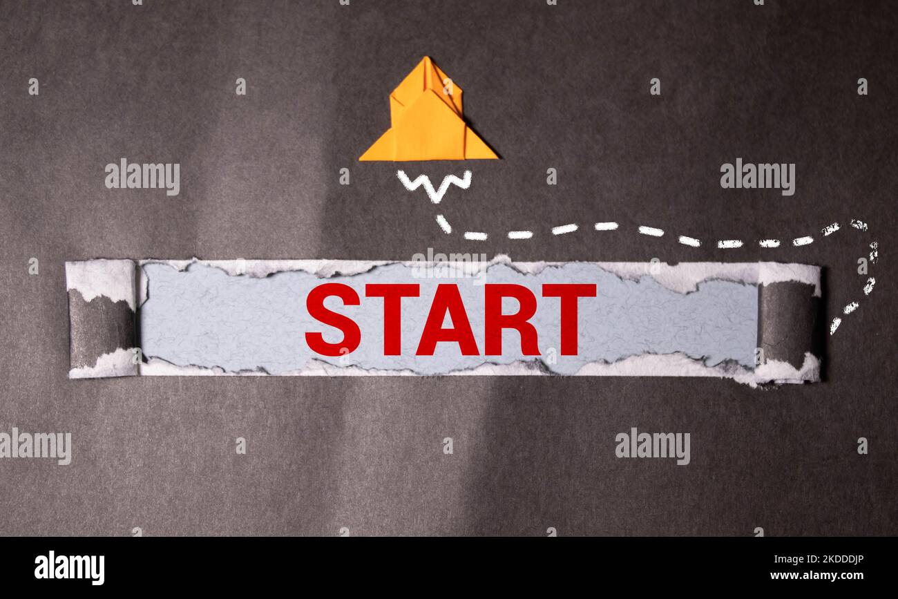 Hand drawing the Word Start in the Green Sand. Male hand writes the ...