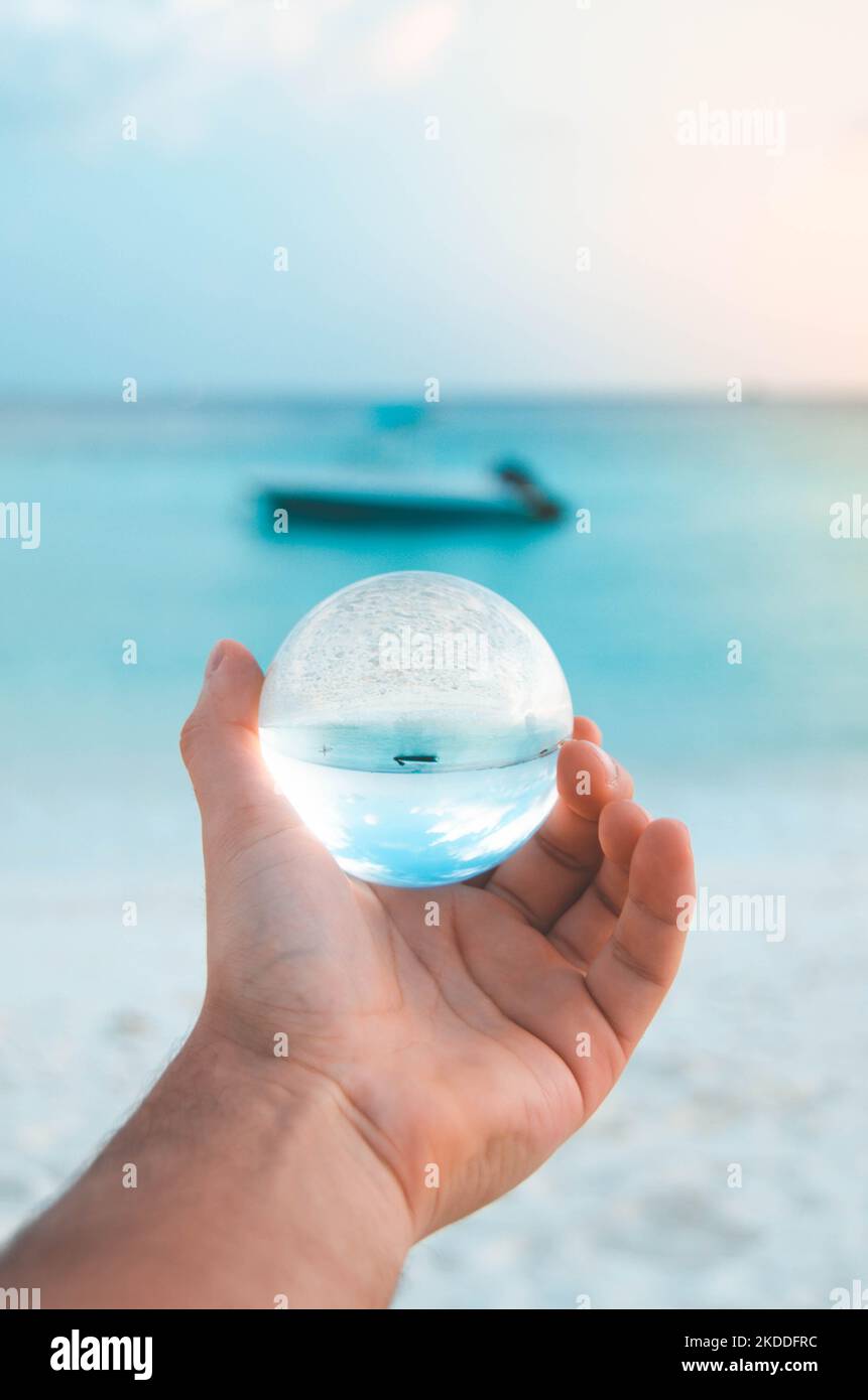 A hand holding a glassball and pointing it to a floating boat Stock ...