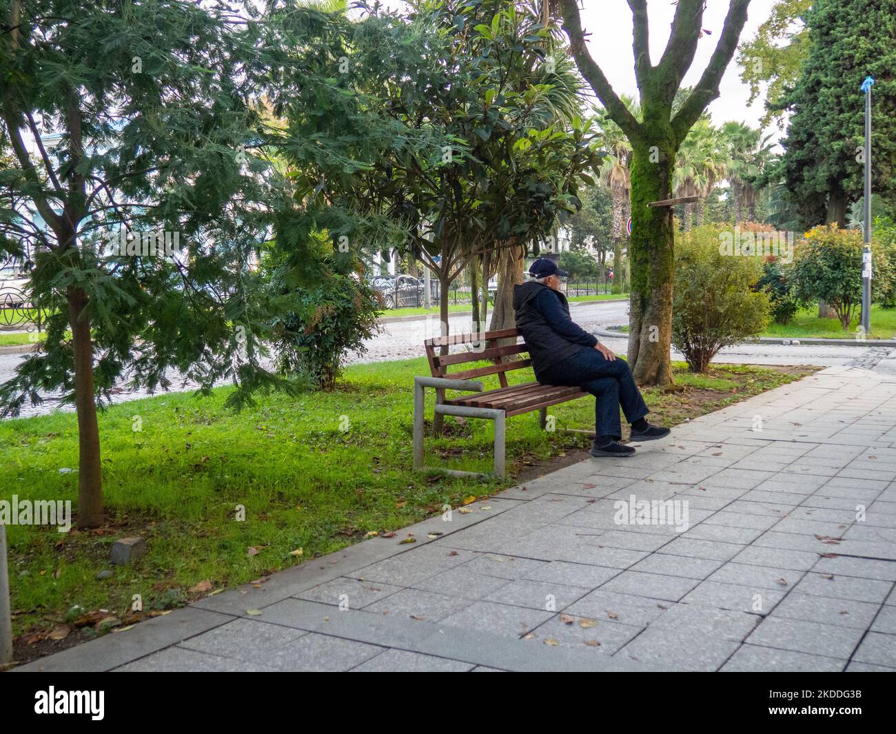 A lonely man sits on a park bench. Urban environment. The man sits on ...