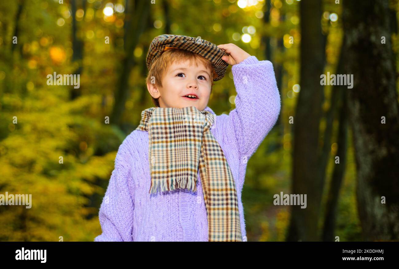 Happy child boy in sweater, scarf and cap. Happy kid outdoors in autumn ...