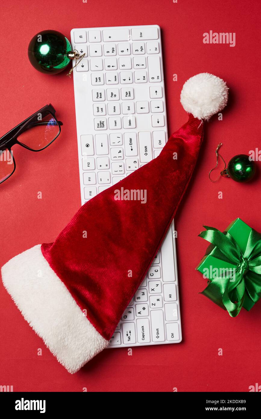 a santa hat, eyeglasses and a computer keyboard on a red background ...