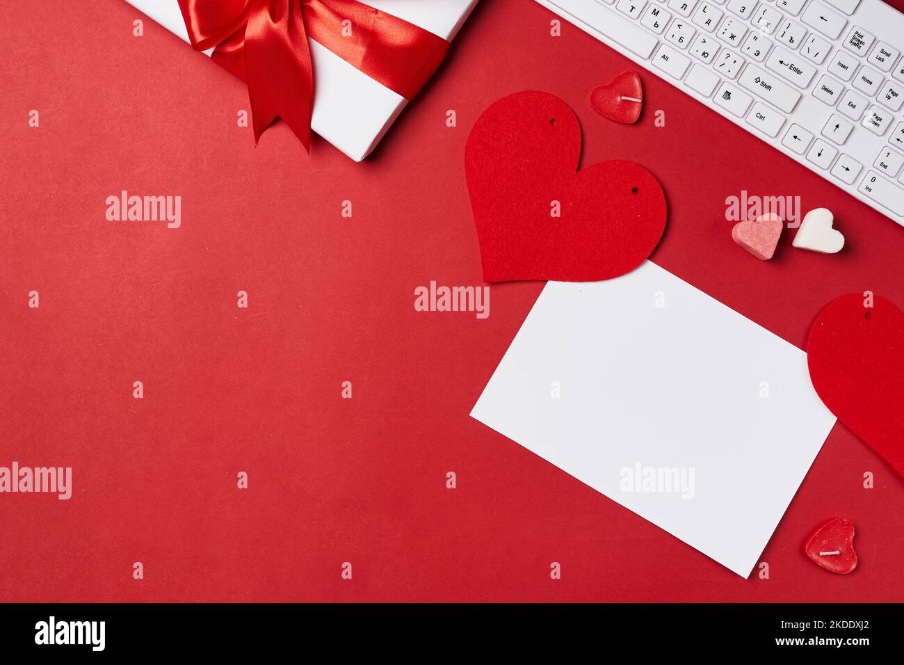 two hearts on top of a computer keyboard with a red ribbon around it ...