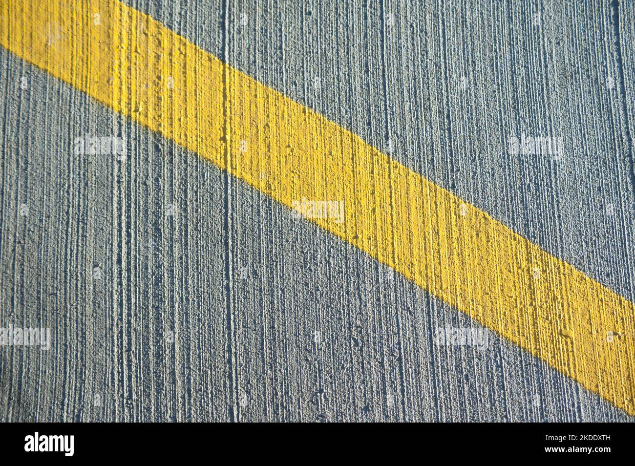 Oblique stripe of yellow paint marked on irregular gray concrete wall ...