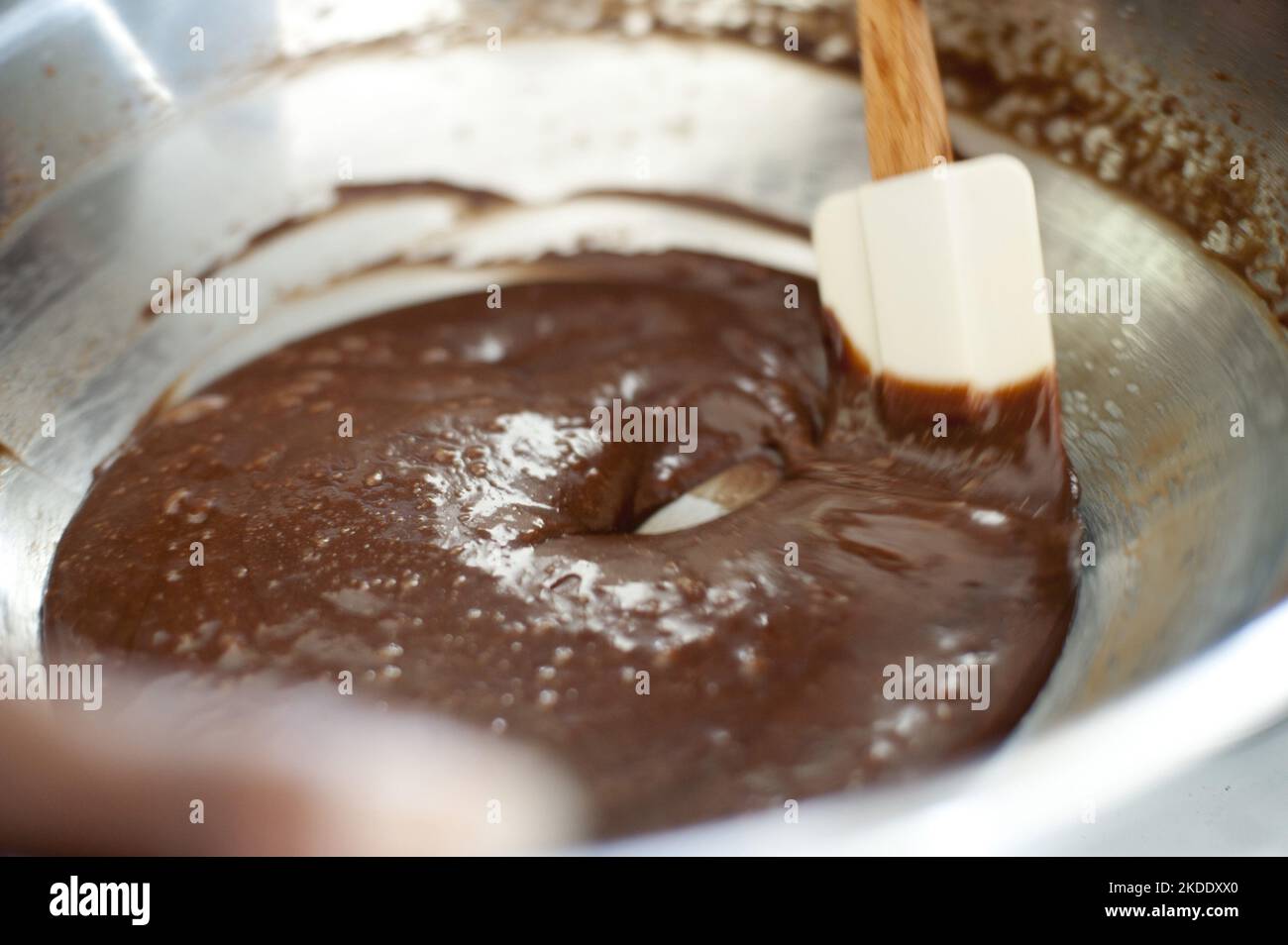 Cook making a bowl of chocolate icing cleaning around the edge of the ...