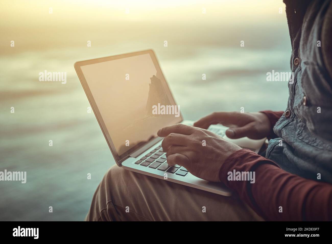 Always connected. an unrecognizable man using his laptop while sitting ...