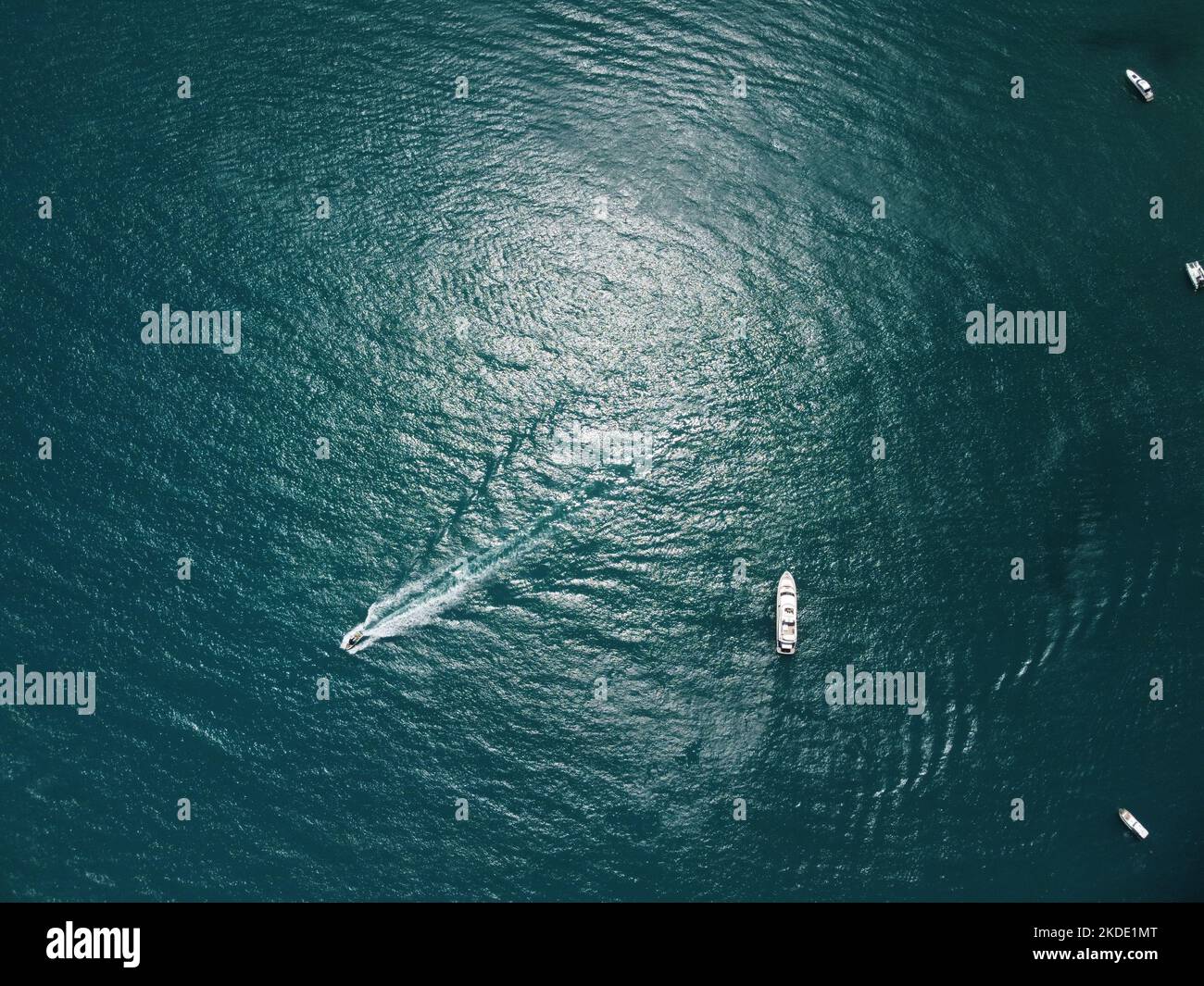 Aerial yacht on calm sea. Luxury cruise trip. View from above of white boat on deep blue water ...