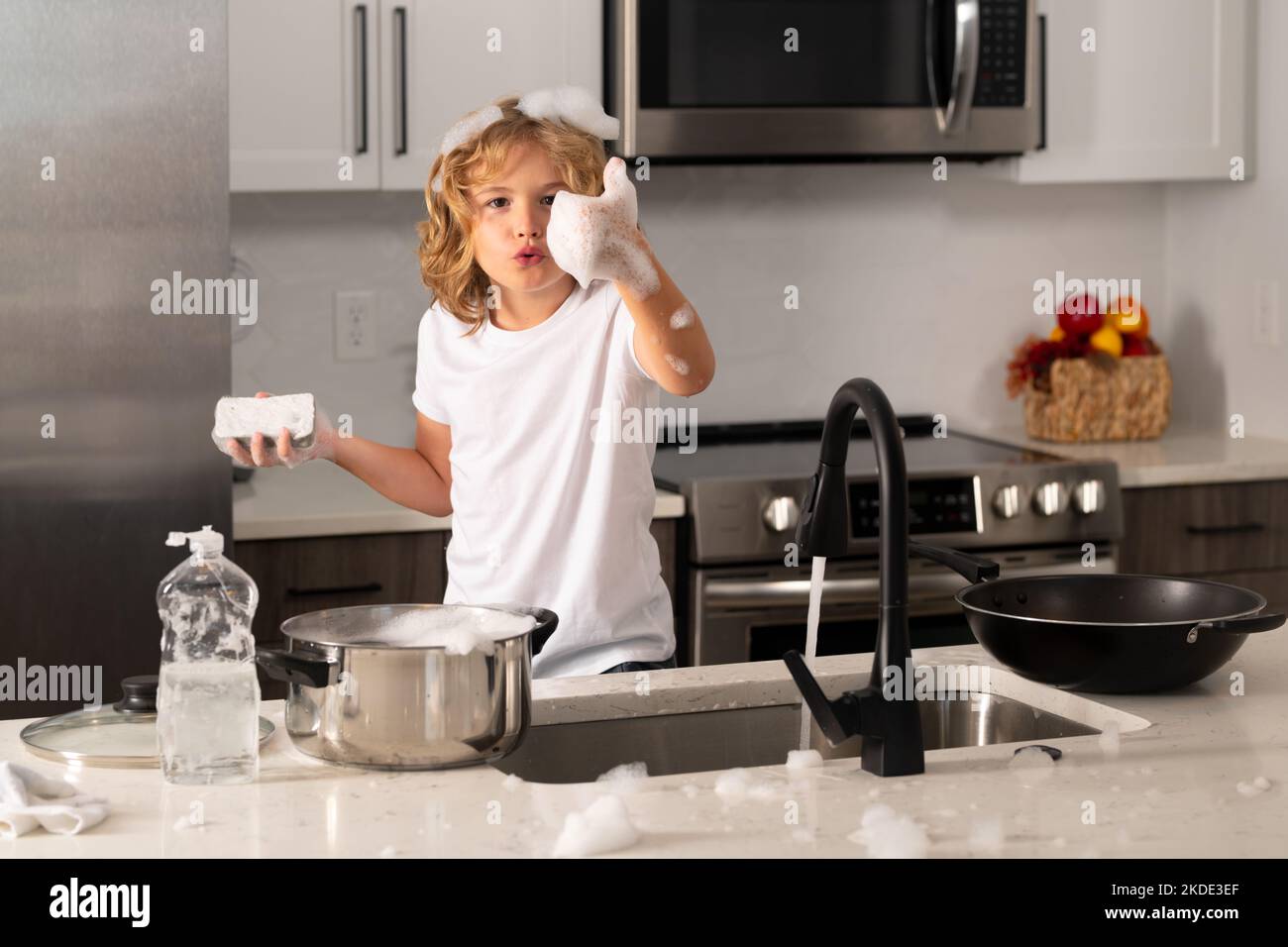 Kid boy washing dishes in the kitchen interior. Clean washed dishes ...